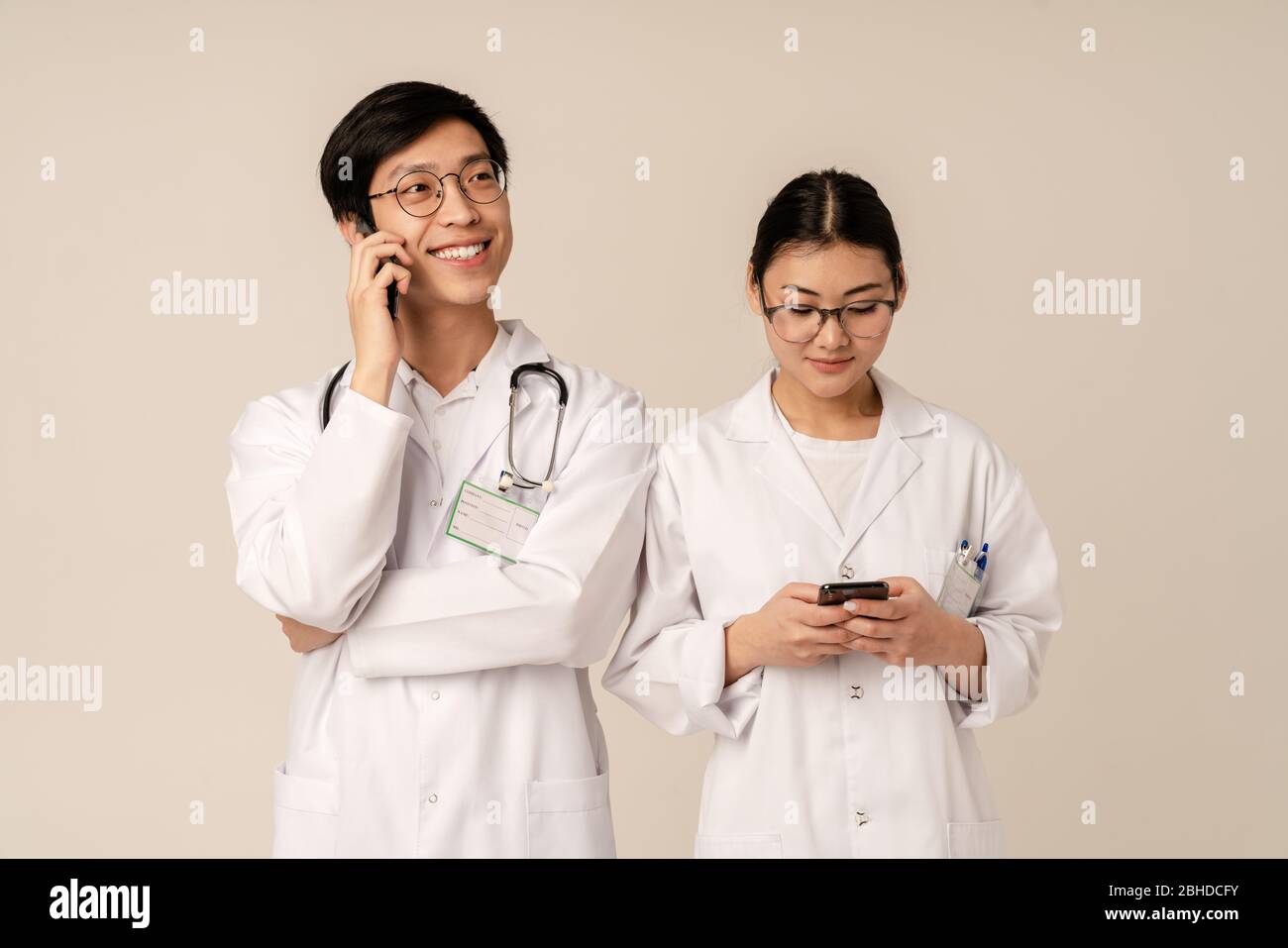 Image of asian young medical doctors in white uniform using cellphones ...