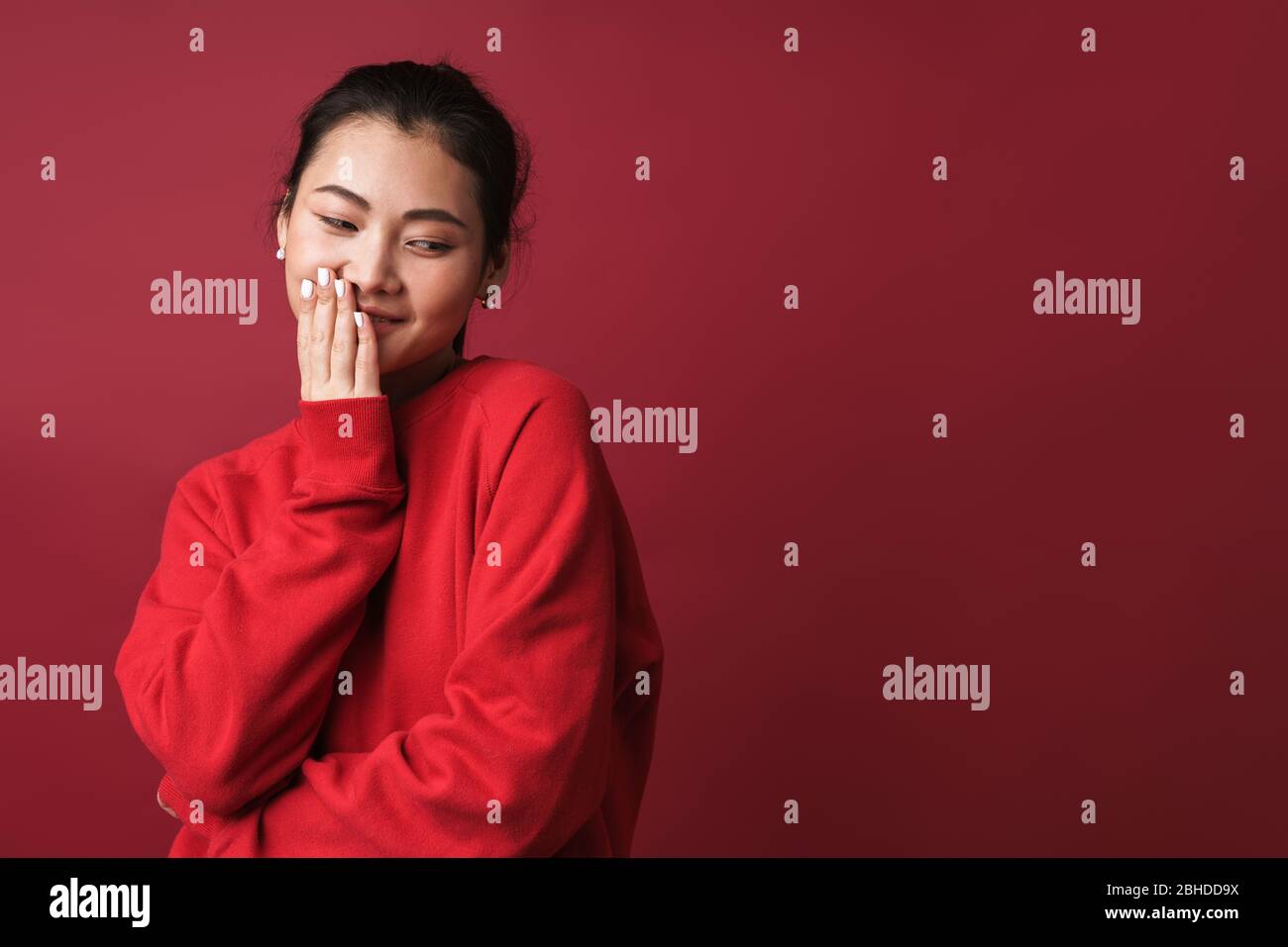 Image of an asian cheerful shy happy young woman posing isolated over ...