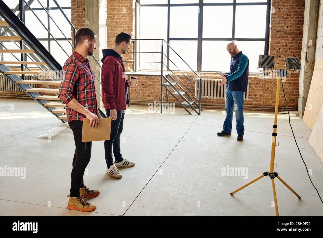 Three young engineers measuring length of floor panels while preparing ...