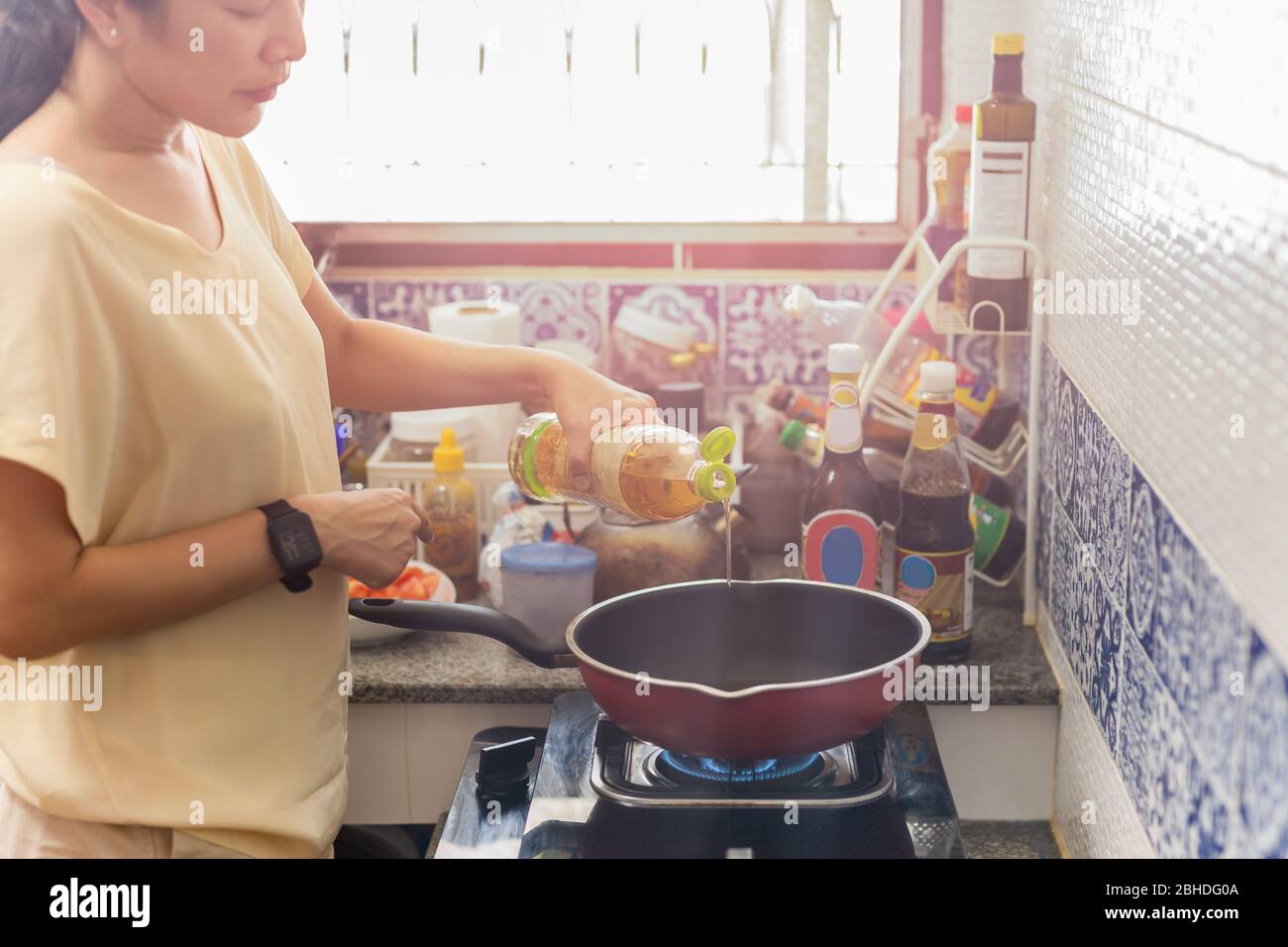 Woman pouring cooking oil from bottle into frying pan Stock Photo - Alamy