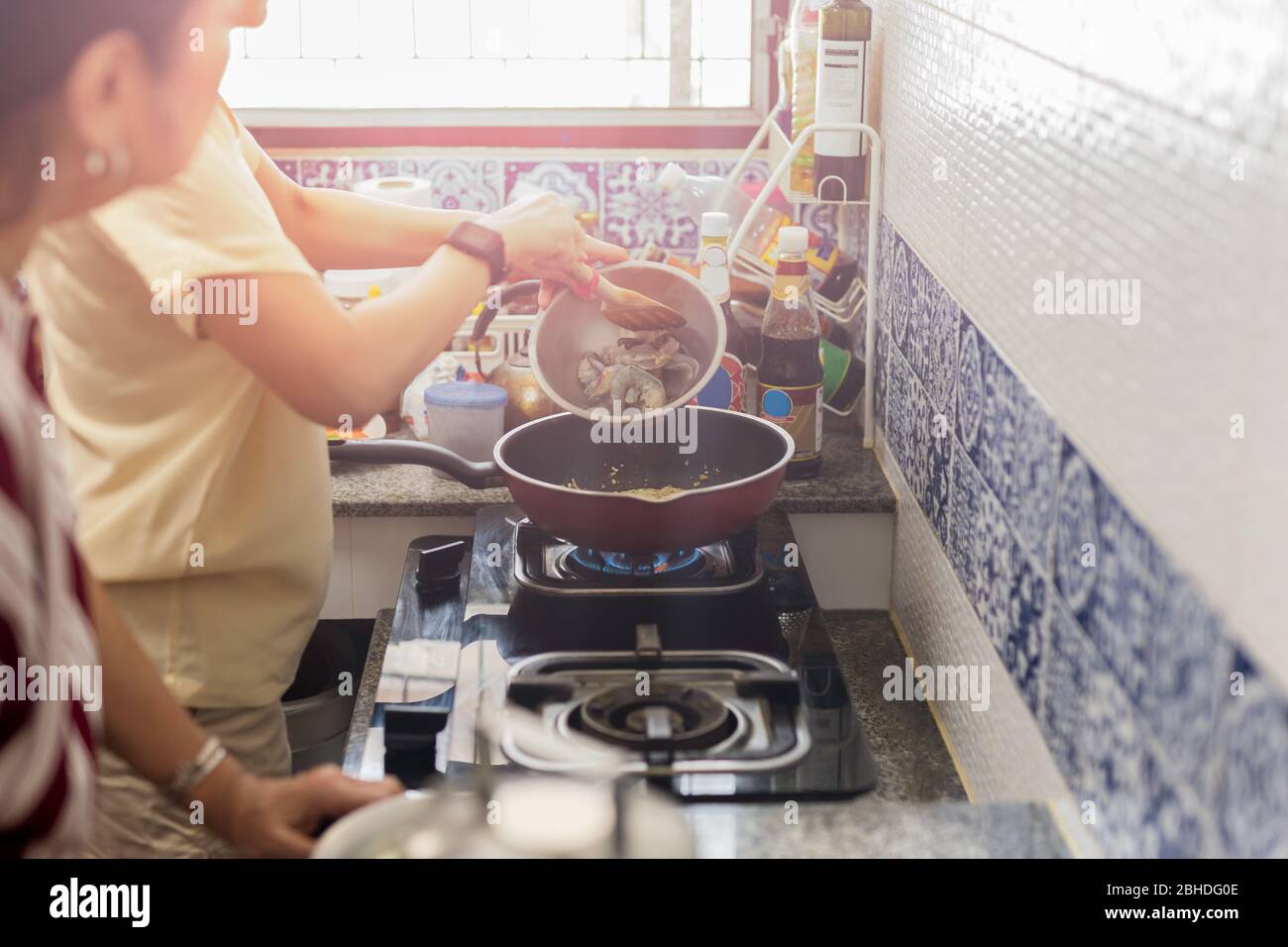 Asian woman in the kitchen cooking food with her mum during covid-19 ...