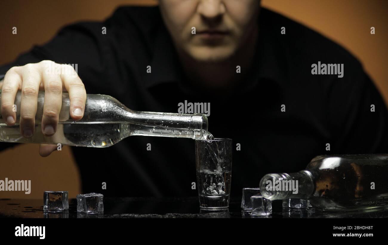Depressed blurred man alcoholic pour vodka, rum, liquor in a shot ...