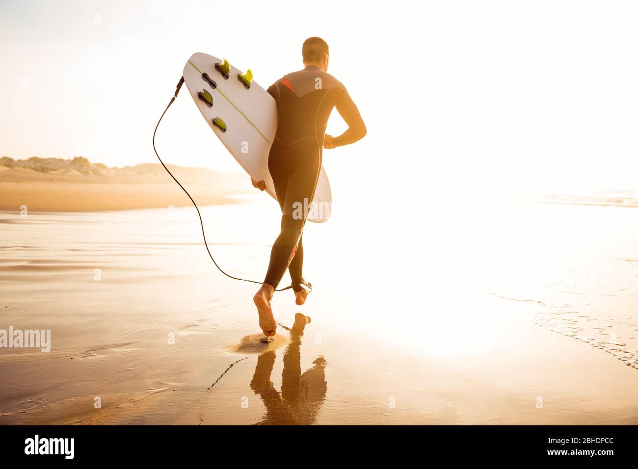 A surfer with his surfboard running to the waves Stock Photo - Alamy