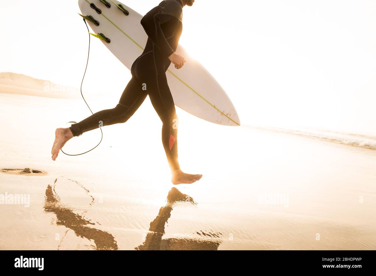 A surfer with his surfboard running to the waves Stock Photo - Alamy
