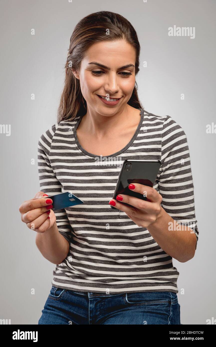 Beautiful happy young woman sitting on a bench and shopping online ...