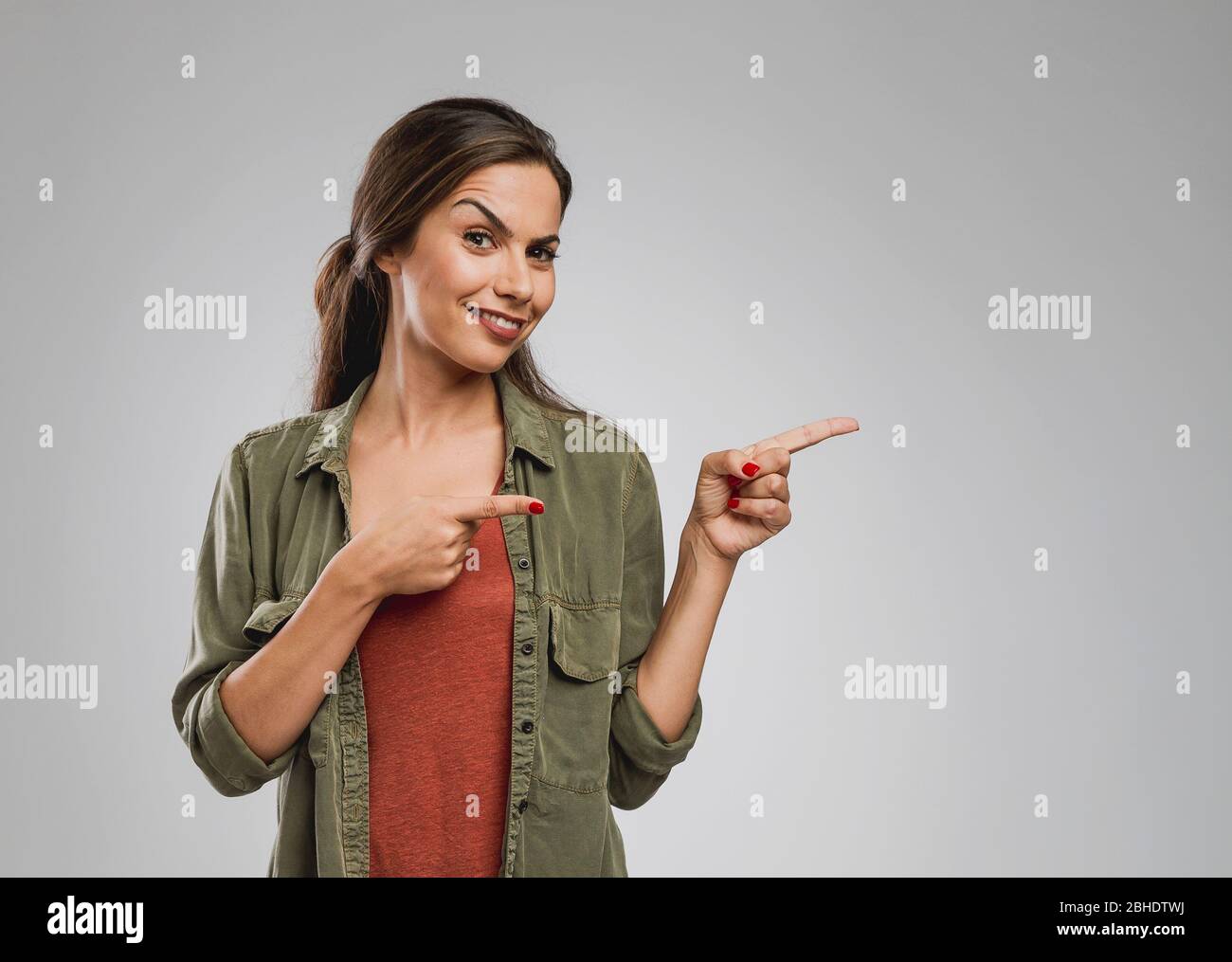 Beautiful woman over a gray background pointing to her left side Stock ...