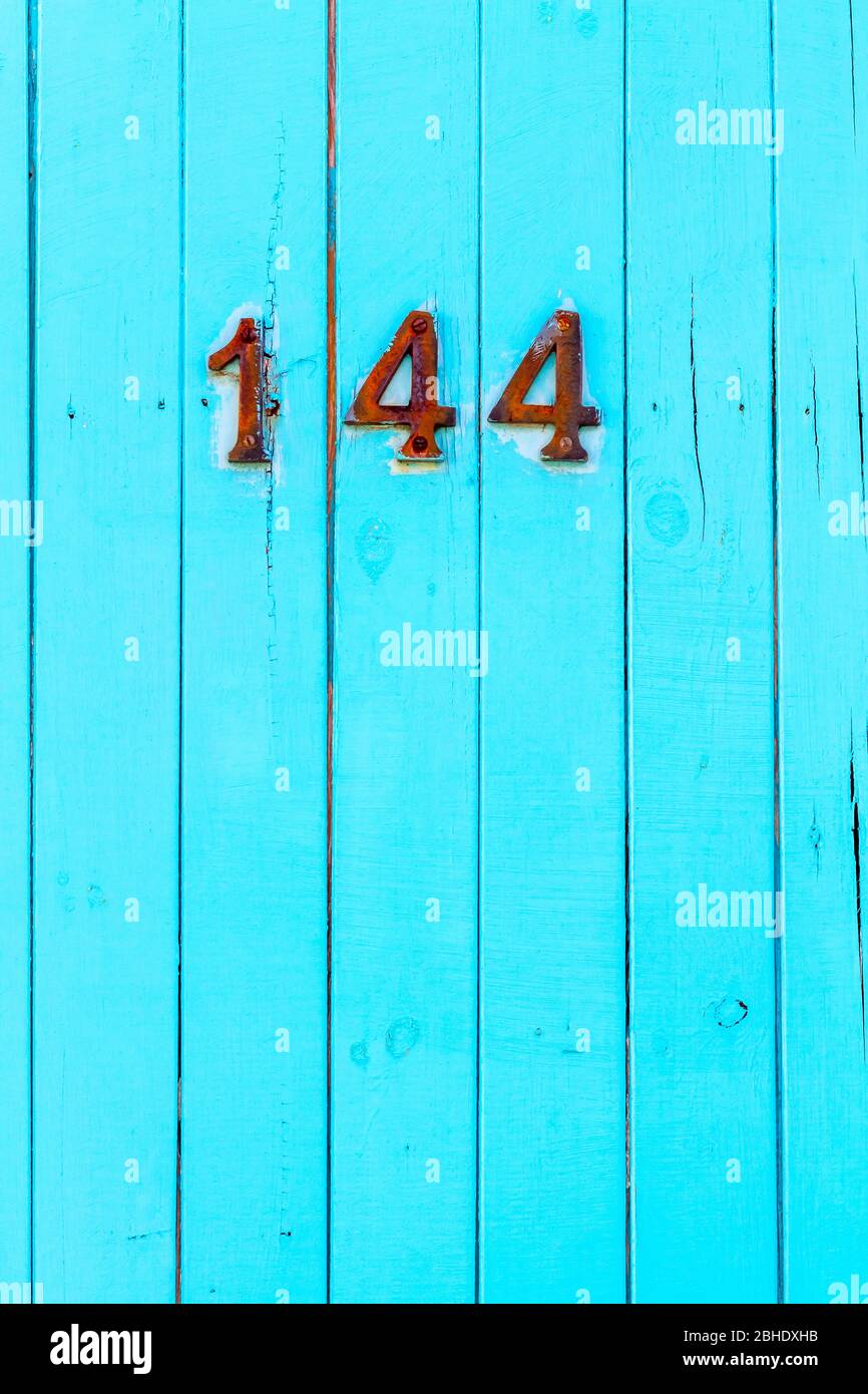 House number 144 on a bright blue wooden gate Stock Photo - Alamy