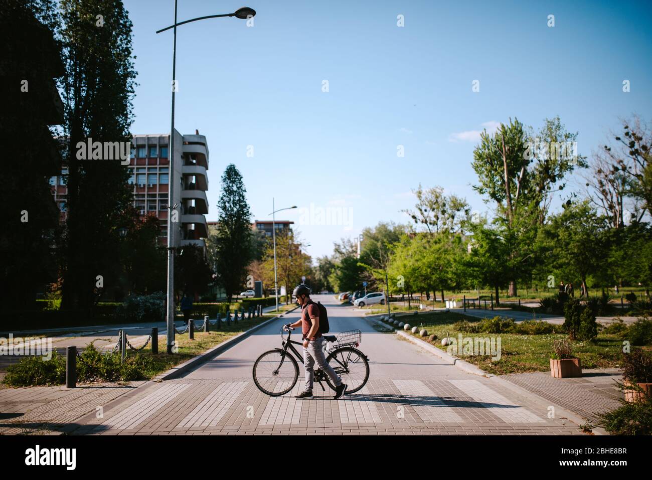 Handsome young caucasian cyclist with helmet and backpack cycling in ...