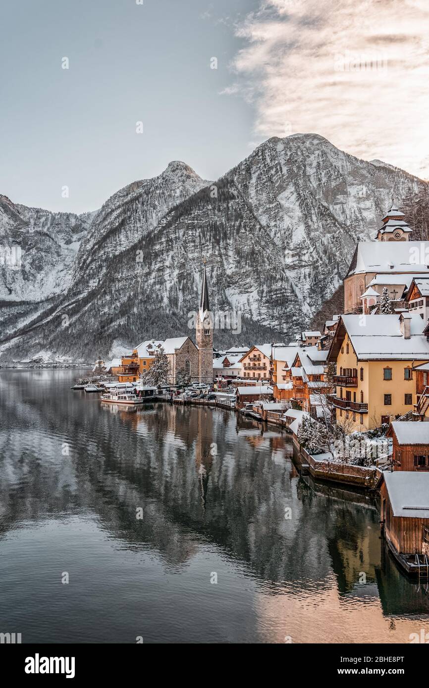 Snowy village Hallstatt by lake at foot of snow mountain with clear sky ...