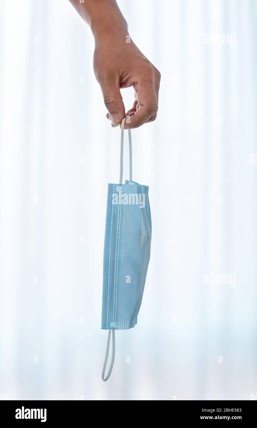 Hand holding a surgical face mask, ready to dispose Stock Photo - Alamy