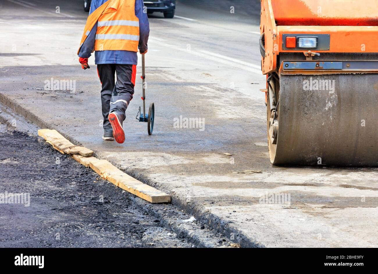 An engineer measuring road distances with a measuring wheel walks near ...