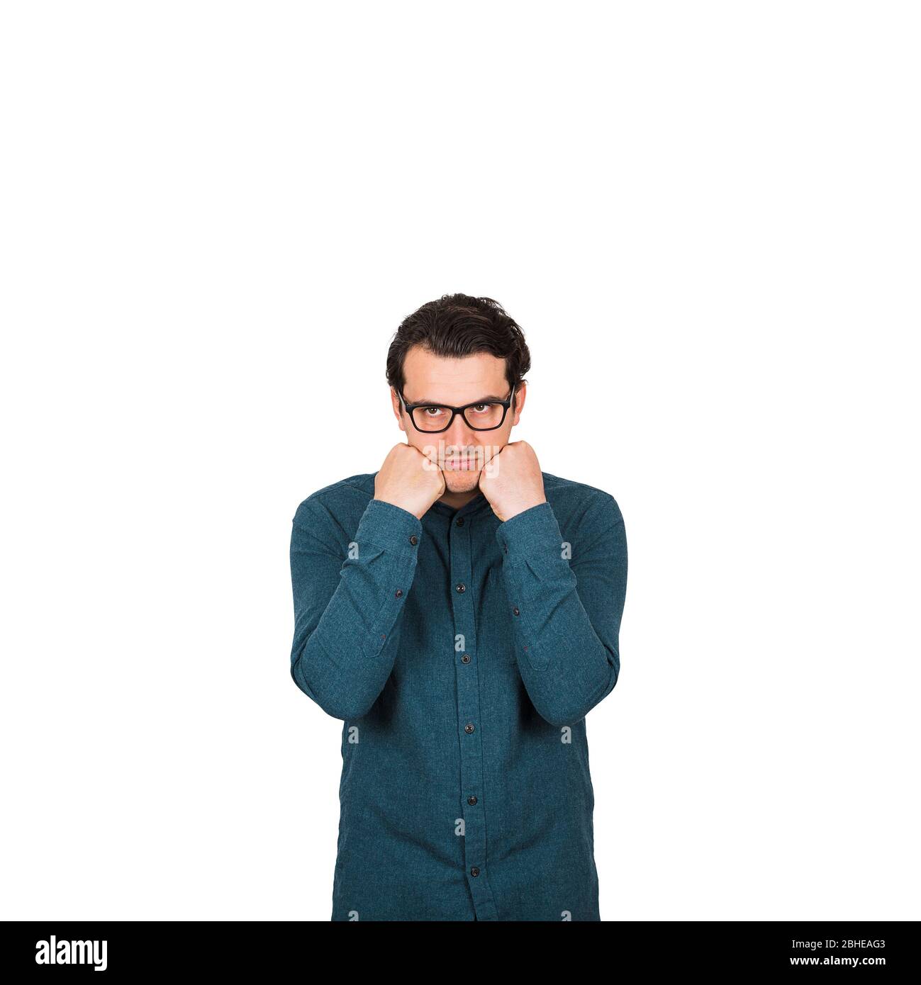 Angry businessman keeps both hands under cheek, clenched fists, makes a ...