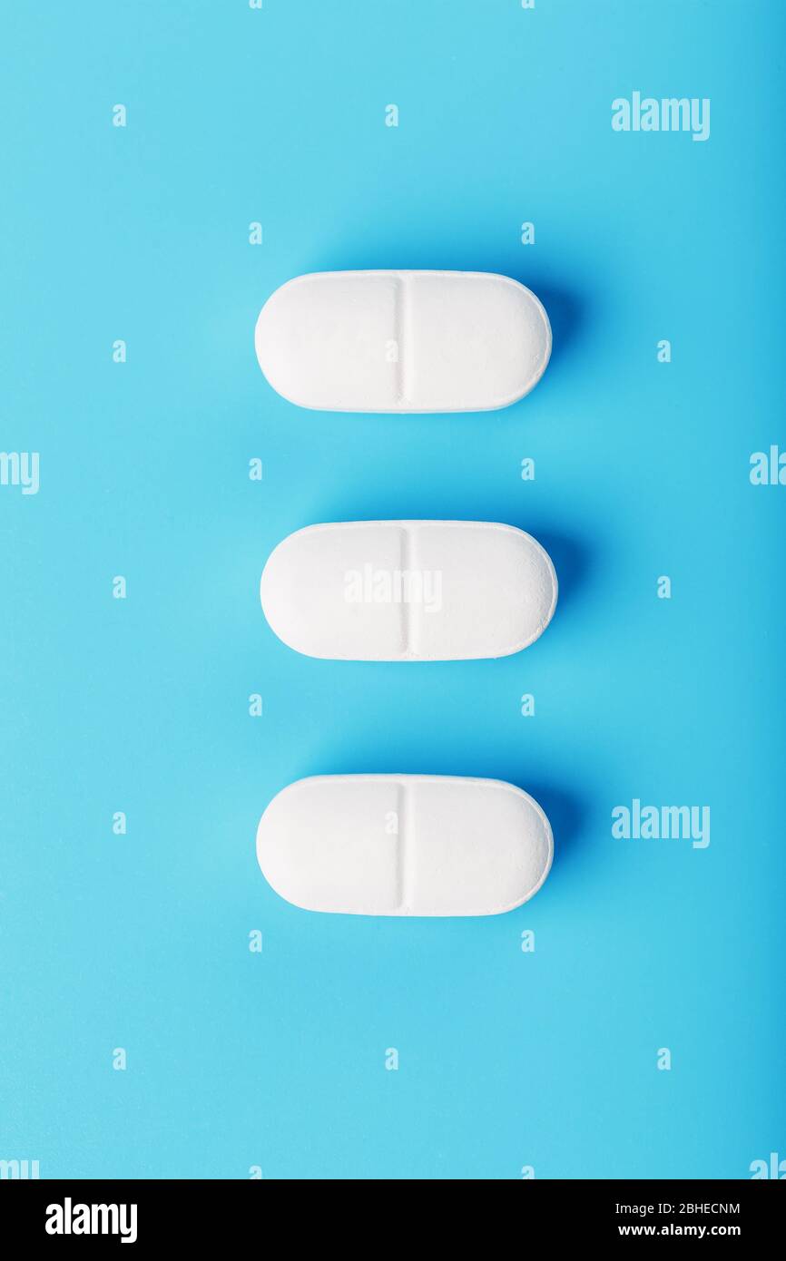 Three medicinal tablets in a row on a blue background, isolate. the ...