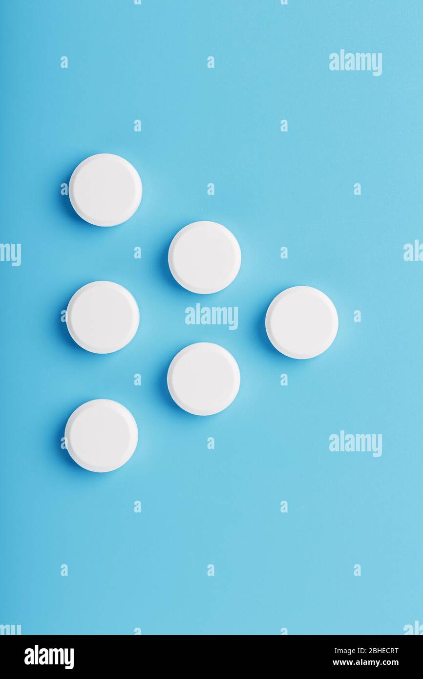 Round medicinal tablets in the shape of a triangle on a blue background ...
