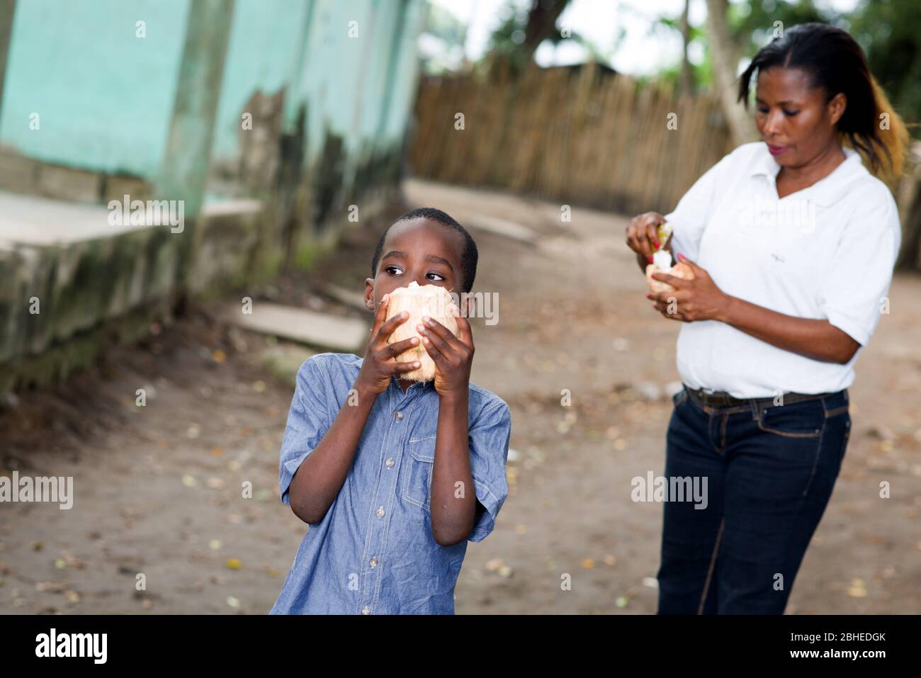 mother and child eating a coconut while walking in the street. family ...