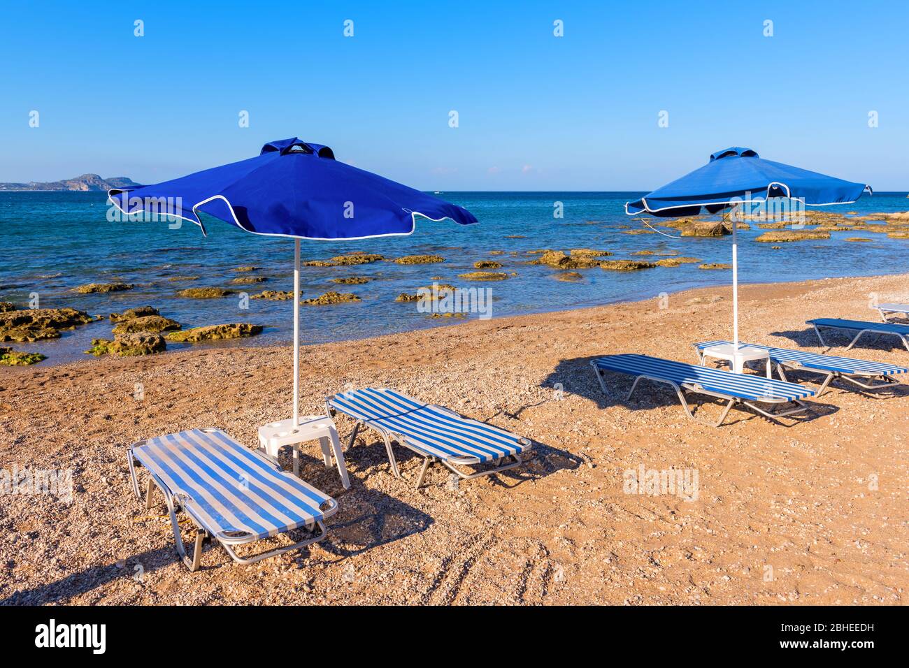 Sun loungers with umbrella on beautiful Kolymbia beach. Rhodes island ...