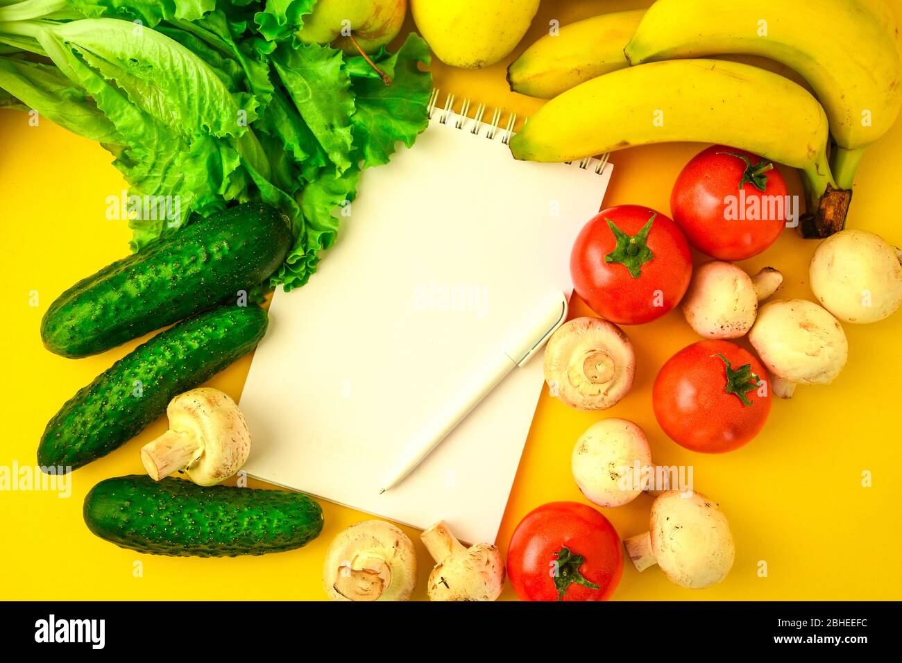 Open recipe book with set of raw organic vegetables on yellow ...