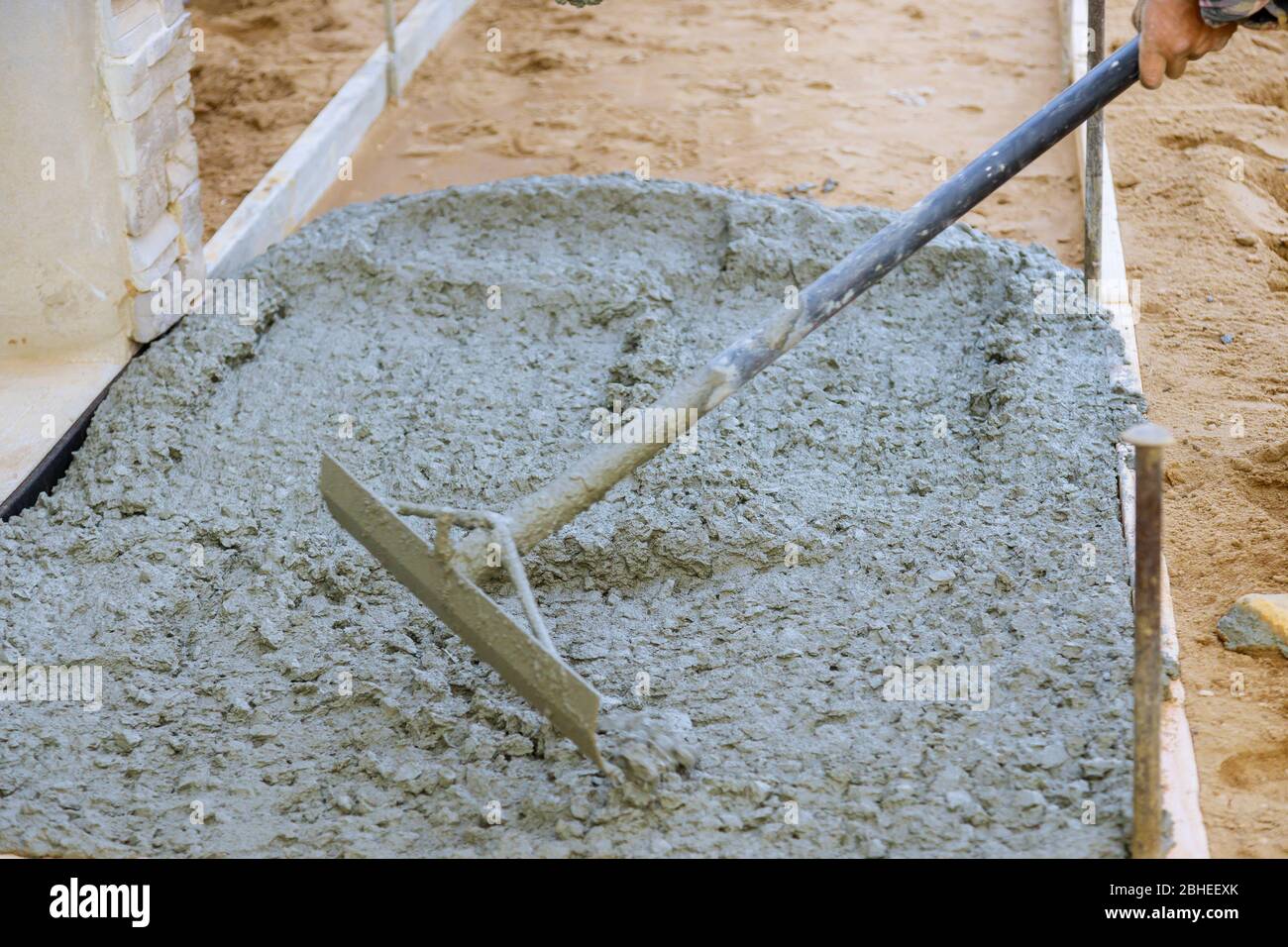 Construction workers leveling concrete pavement sidewalk in new ...