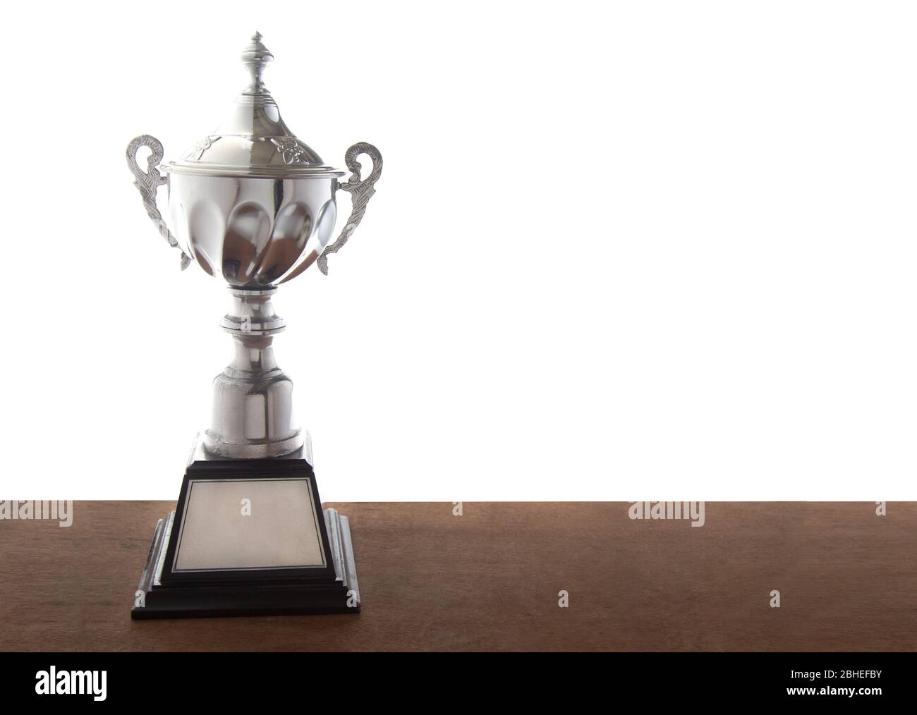 Silver trophy on wooden table isolated over white background. Winning ...