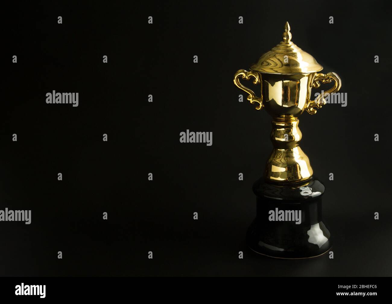 Golden trophy over black background. Winning awards with copy space for ...