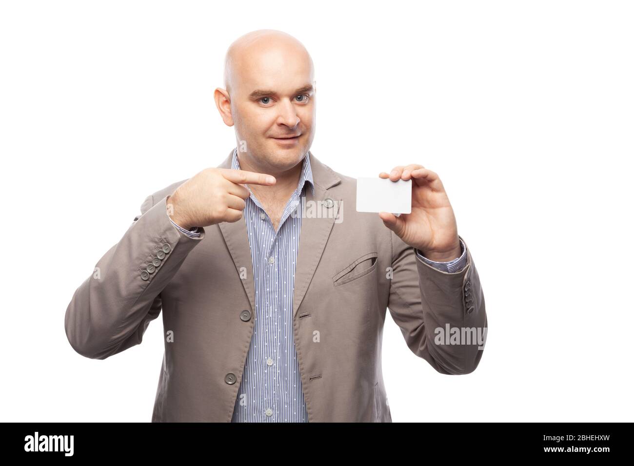 A bald man in a beige suit shows a business card isolated on white ...