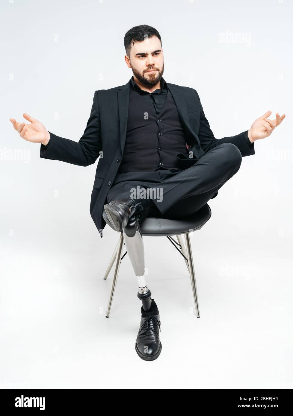 Disabled young man with prosthetic leg sitting on a chair in studio ...