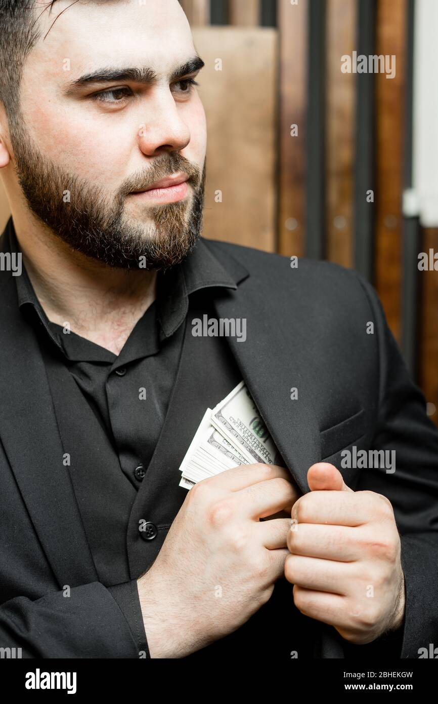 Young man with beard Putting dollars Money In His Pocket Stock Photo ...