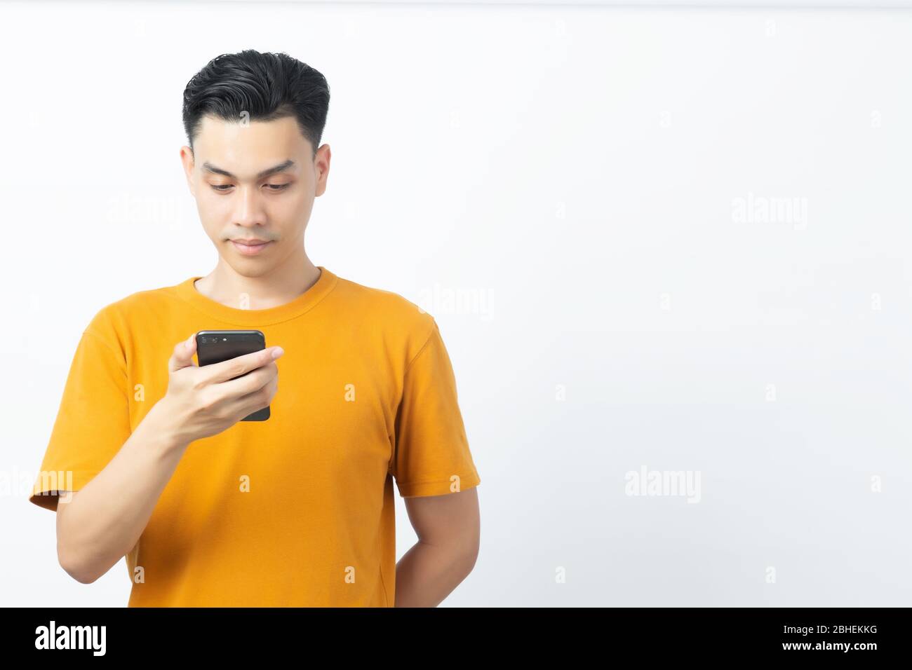 Young happy Asian man reading message from smartphone with copyspace on ...