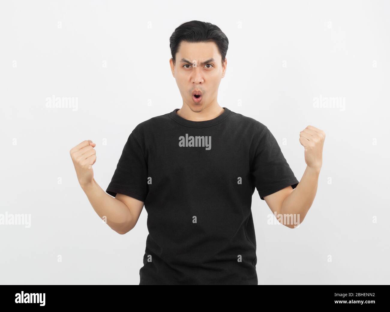 Excited young Asian man raising his fists with happy delighted face ...
