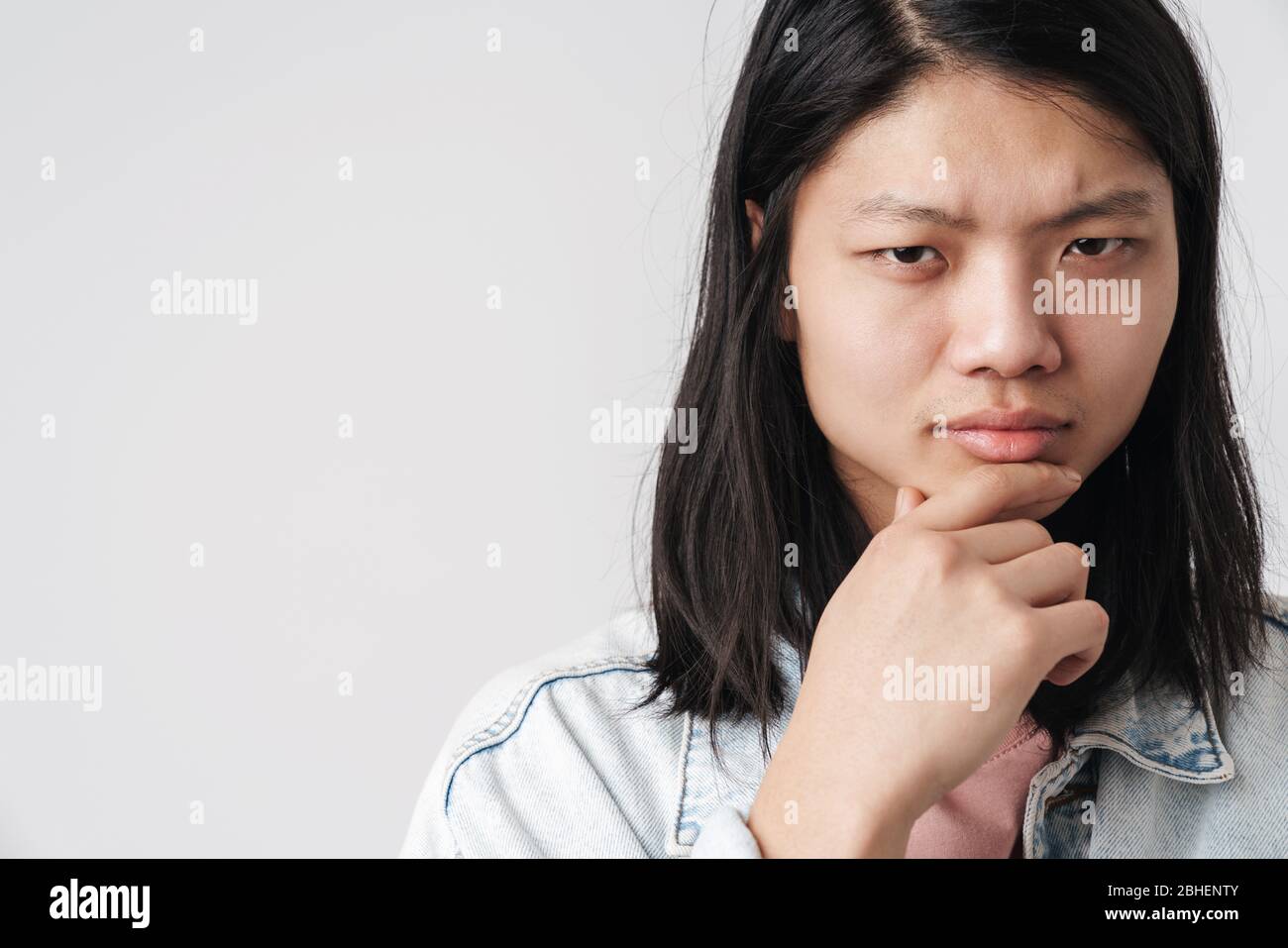 Image of thinking asian man posing and looking at camera isolated over ...