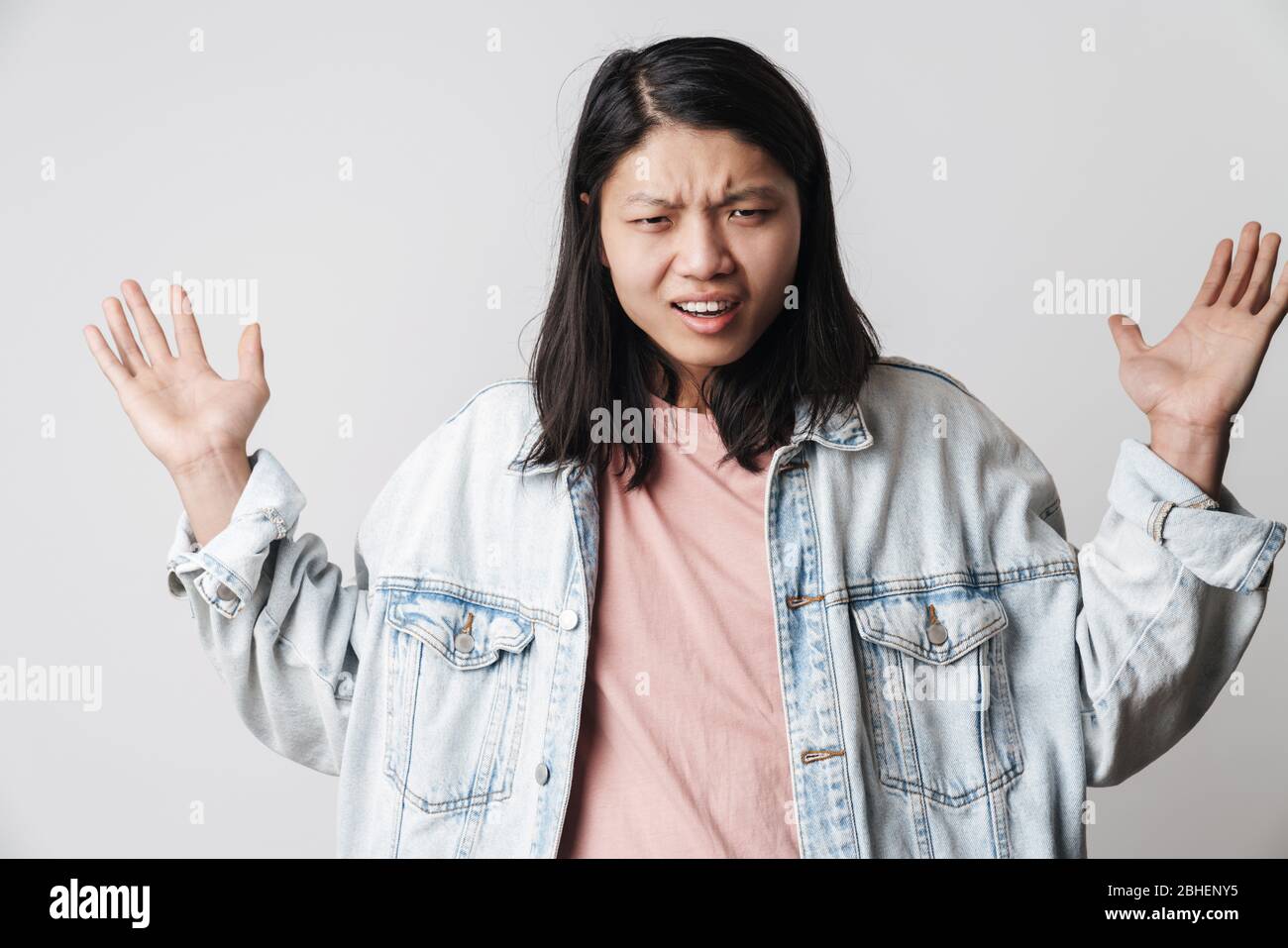 Image of displeased asian man posing on camera with throwing up hands ...