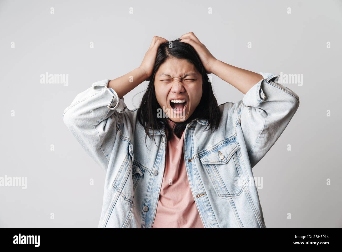 Image of annoyed asian man screaming and grabbing his head isolated ...