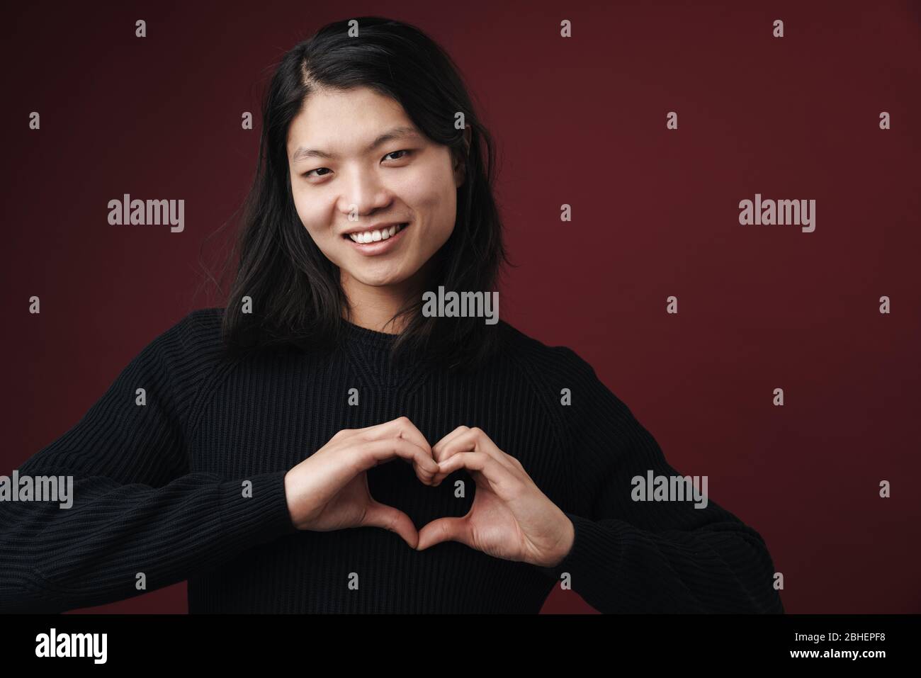 Image of smiling asian man making heart gesture with fingers isolated ...
