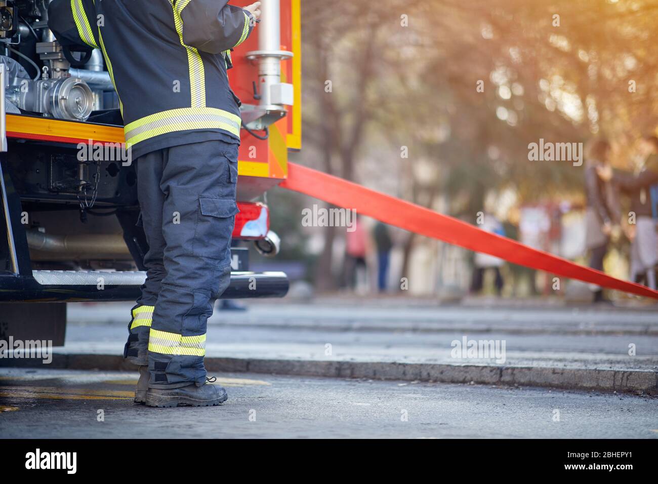 Firefighter in protective uniform. Fireman standing near a fire truck ...