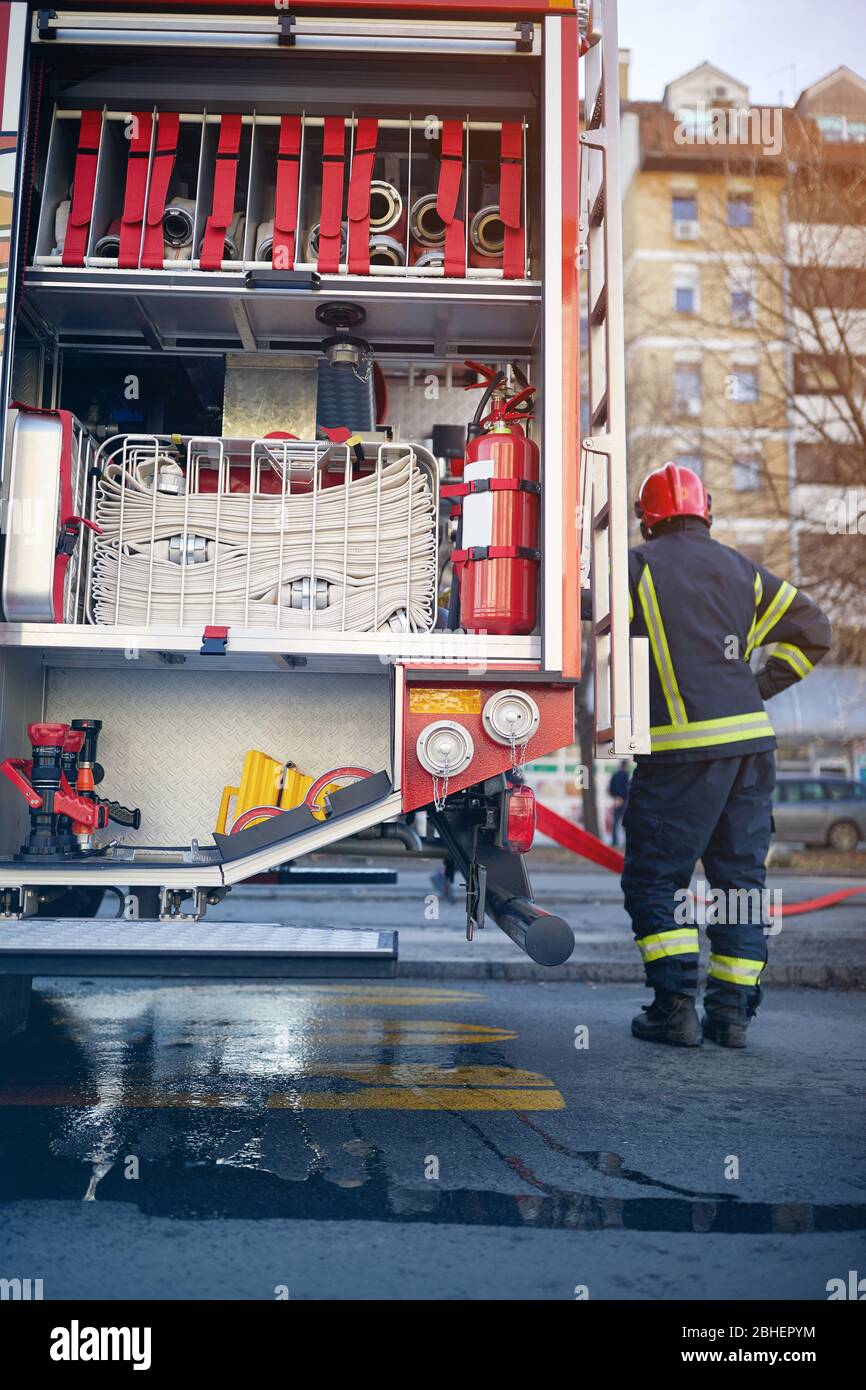 Fire truck with fire fighting equipment.Man firefighter in uniform near ...