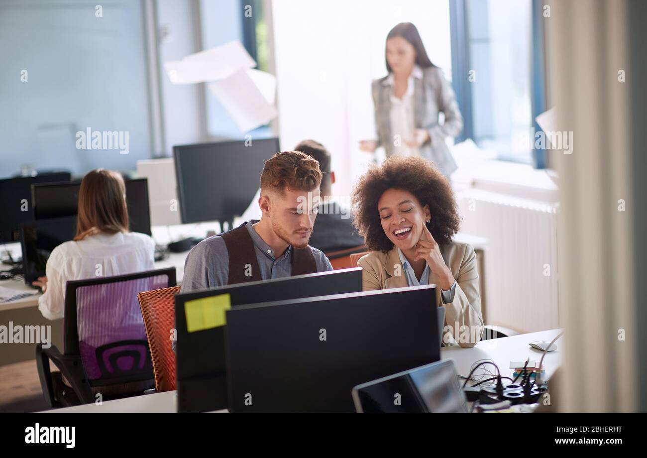 satisfied female boss looking at employees work in open space office ...