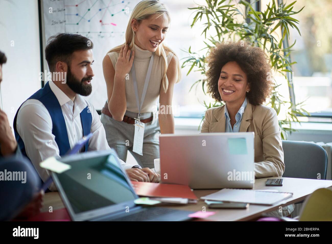 smiling business colleagues looking content on a monitor in modern open ...