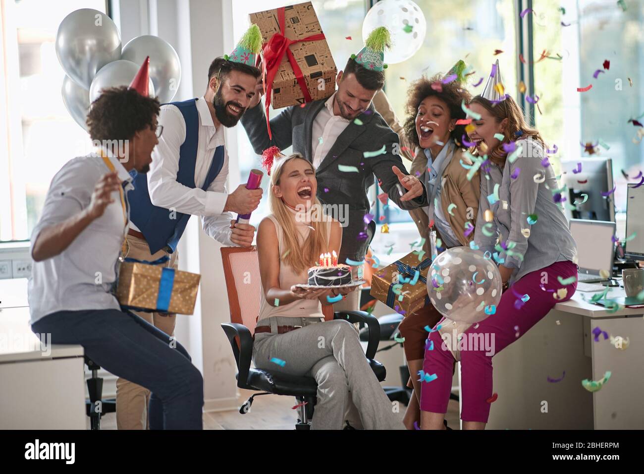 coworkers surprising female colleague with birthday cake at work in ...
