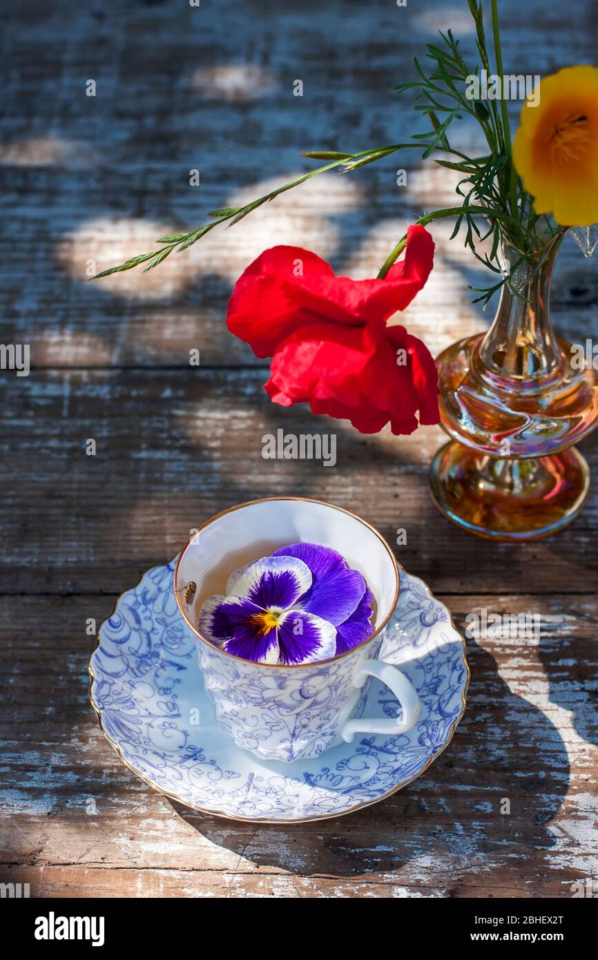 Porcelain cup of tea and beautiful spring flowers in vase on a wooden ...