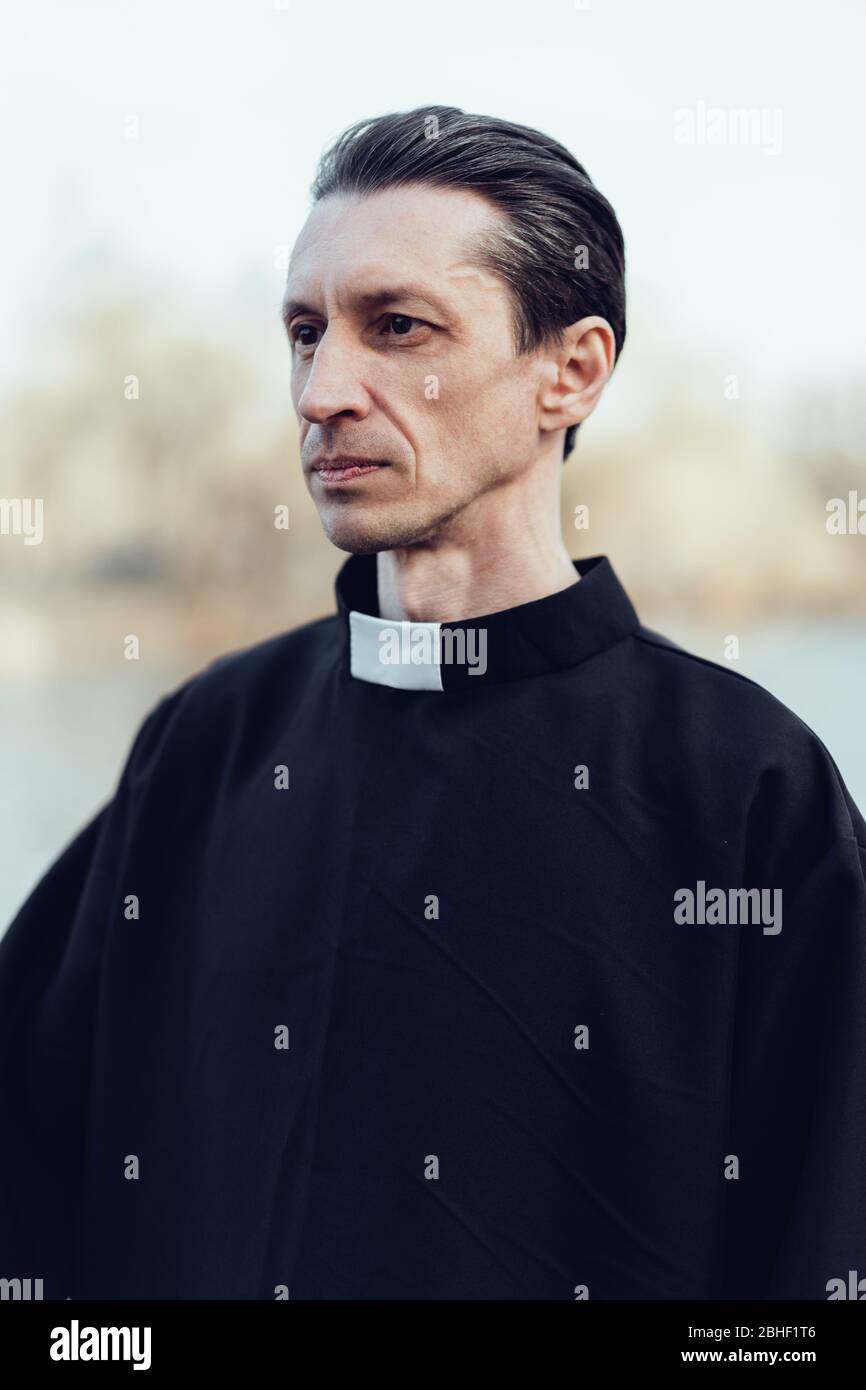 Portrait of handsome catholic priest or pastor with collar Standing ...