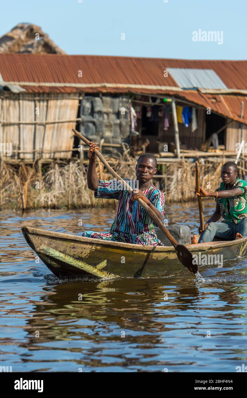 Ganvie village scene with men paddling boat, is a unique village built ...