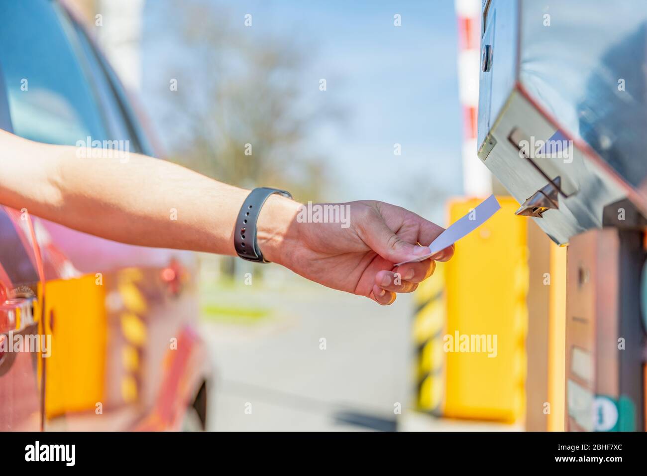 The man takes a parking ticket when entering the paid parking lot by ...