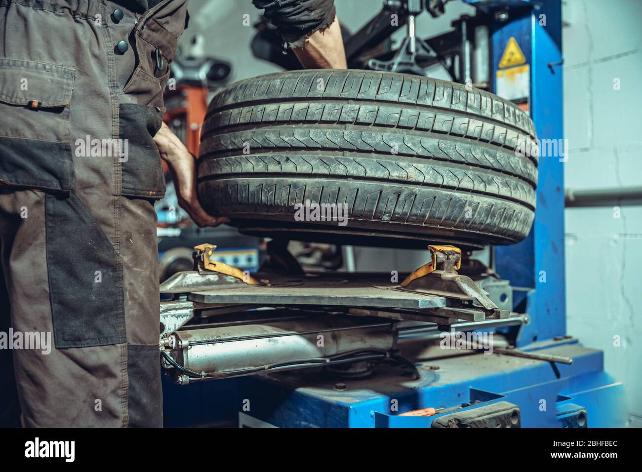 A technician changes tires on a car wheel on a special machine in a ...