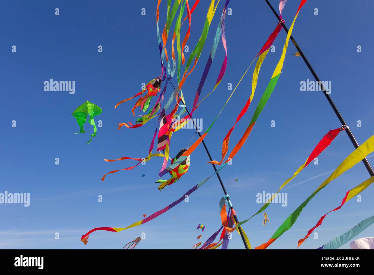 Colorful ribbons hanging on poles on blue sky background kite festival ...