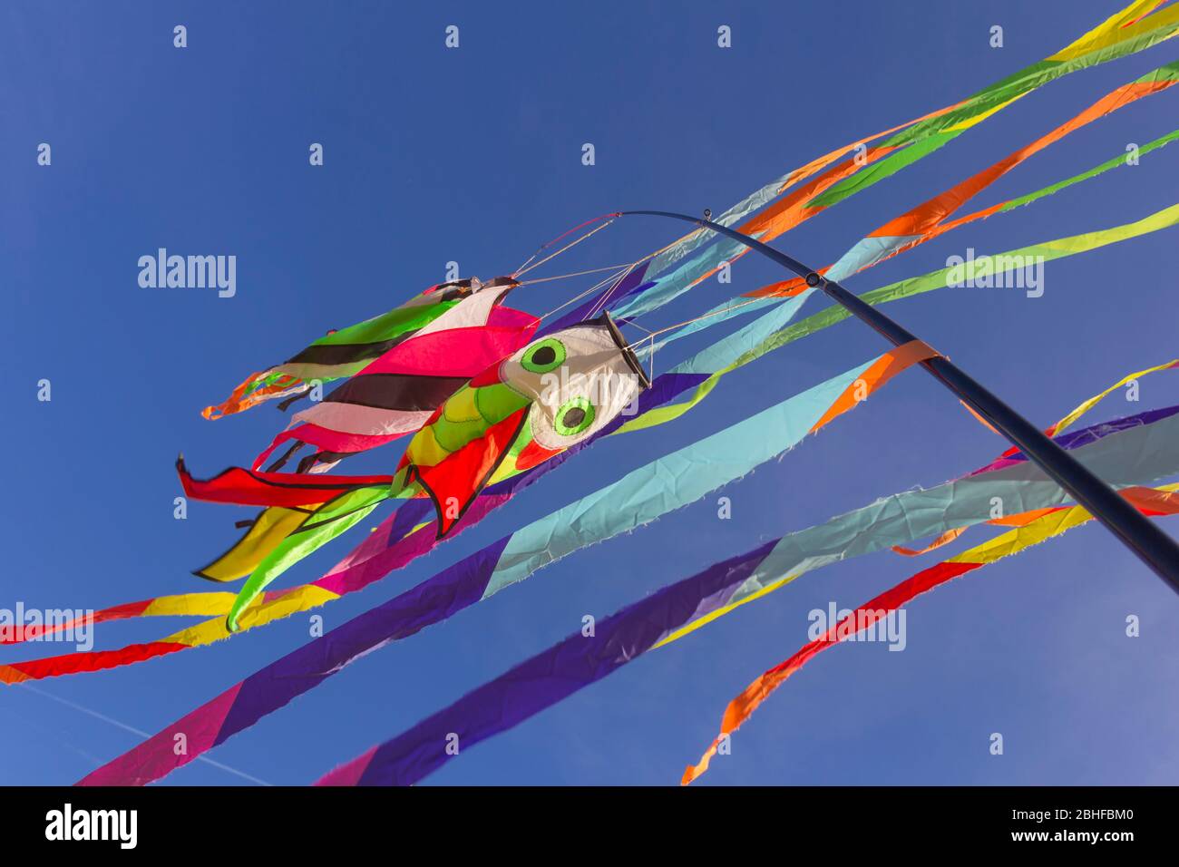 Colorful ribbons hanging on poles on blue sky background kite festival ...