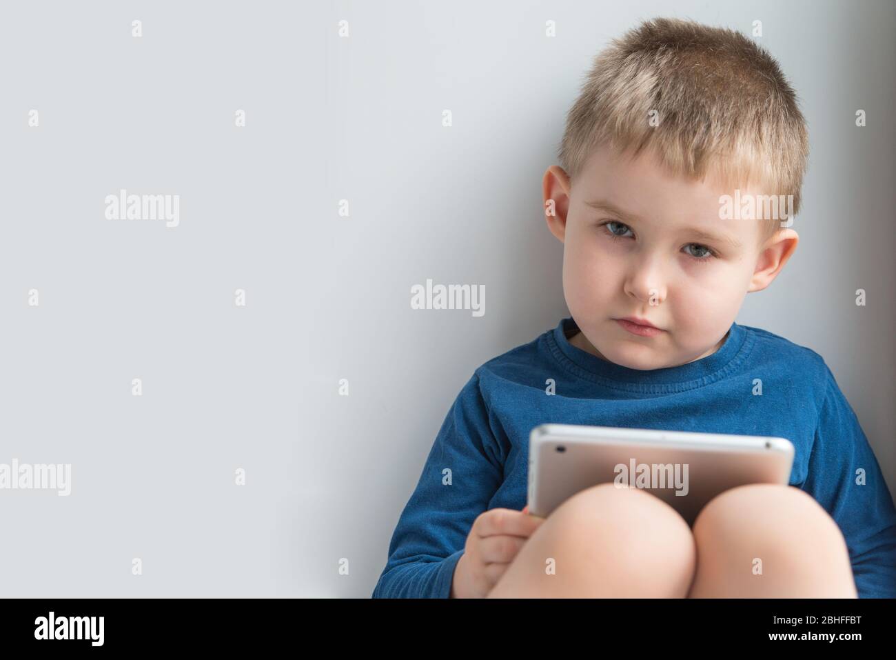 Adorable 4 years old boy portrait in blue longsleeve holding tab gadget ...