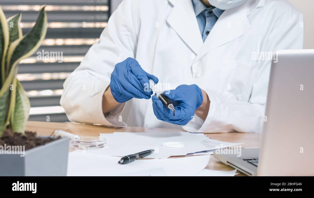 Hand holding syringe with CBD Cannabidiol Hemp paste in a laboratory ...