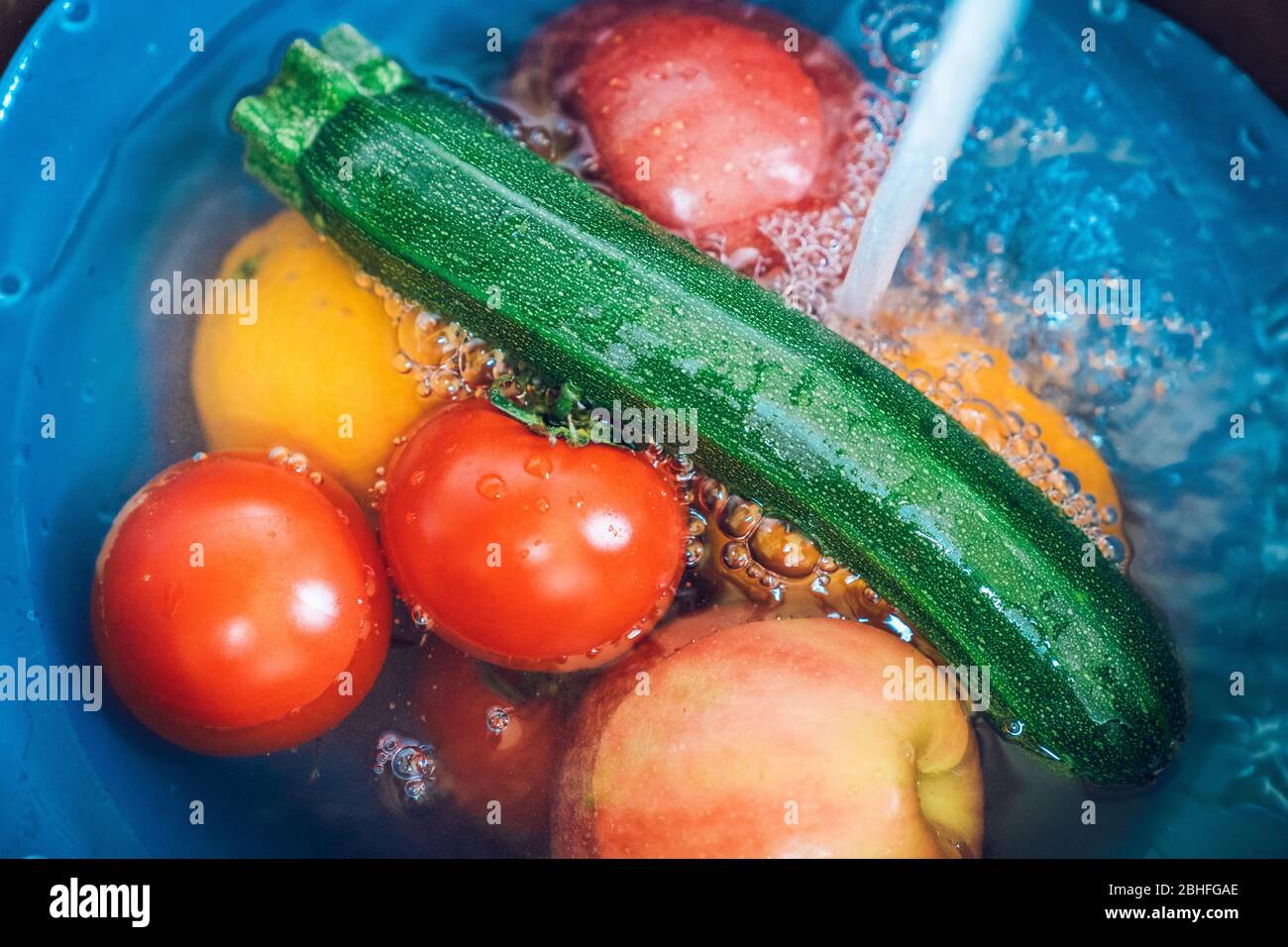Blue bowl full of fruits and vegetables with tap water and lye in the ...
