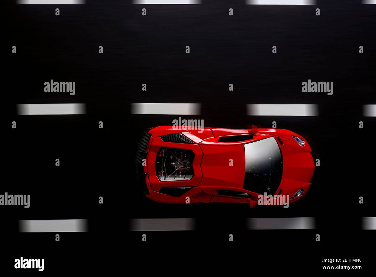 Top view of a red sports car on an asphalt background with road lanes ...