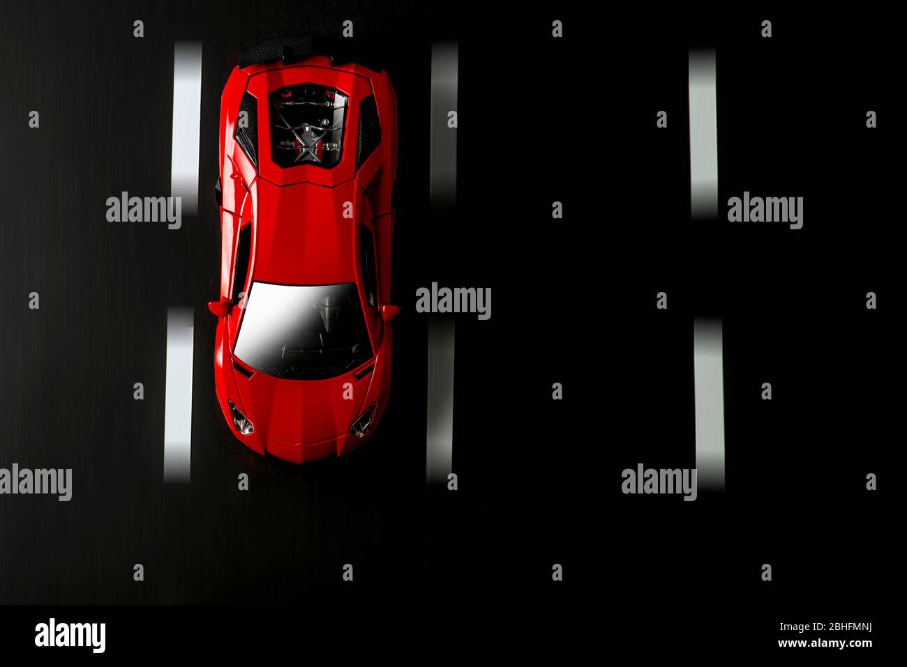 Top view of a red sports car on an asphalt background with road lanes ...